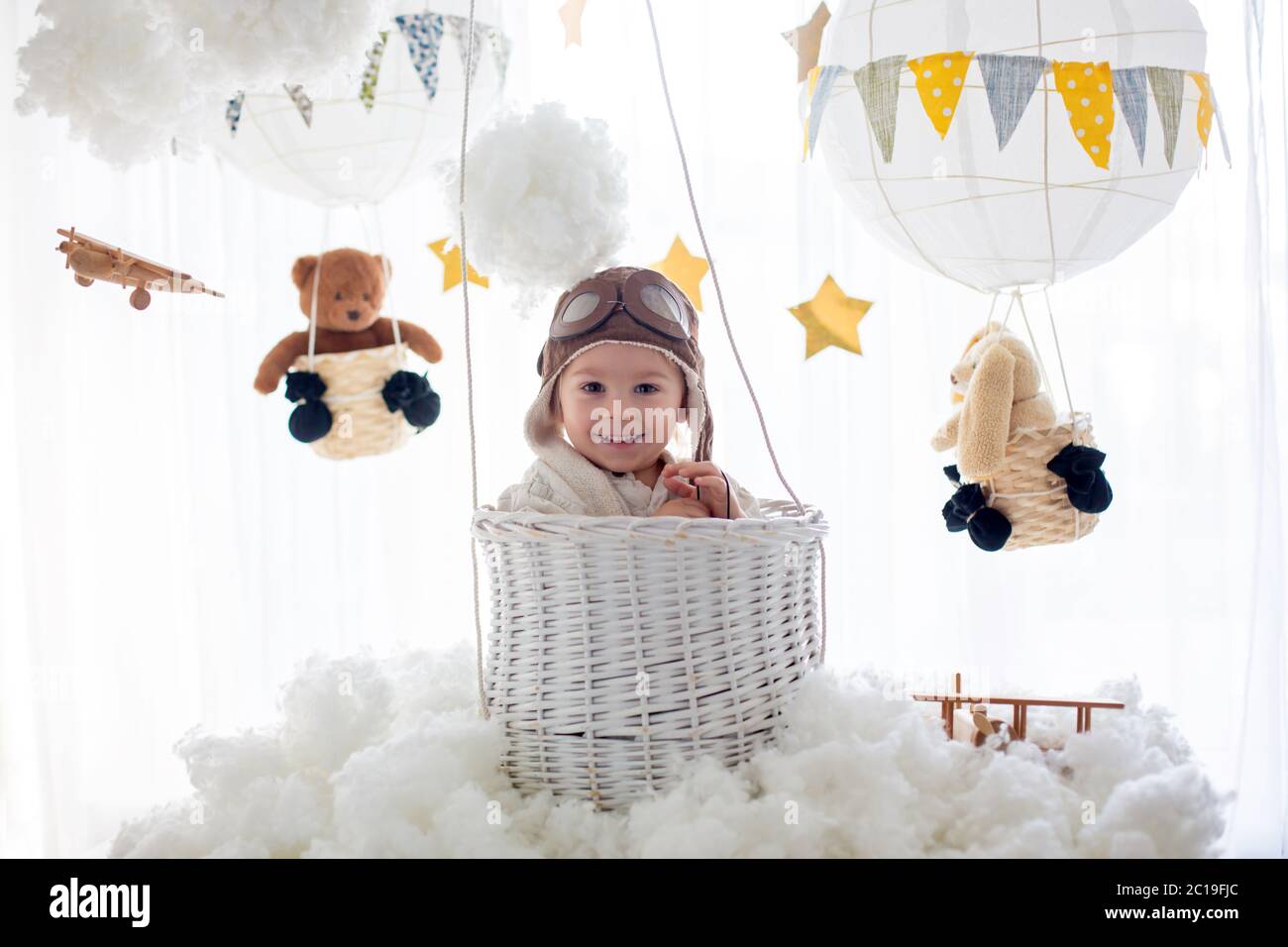 Sweet toddler boy, playing with airplane and teddy bear, decorated air ...