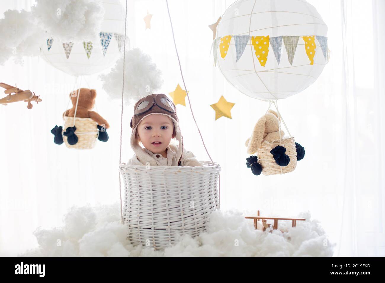 Sweet toddler boy, playing with airplane and teddy bear, decorated air ...