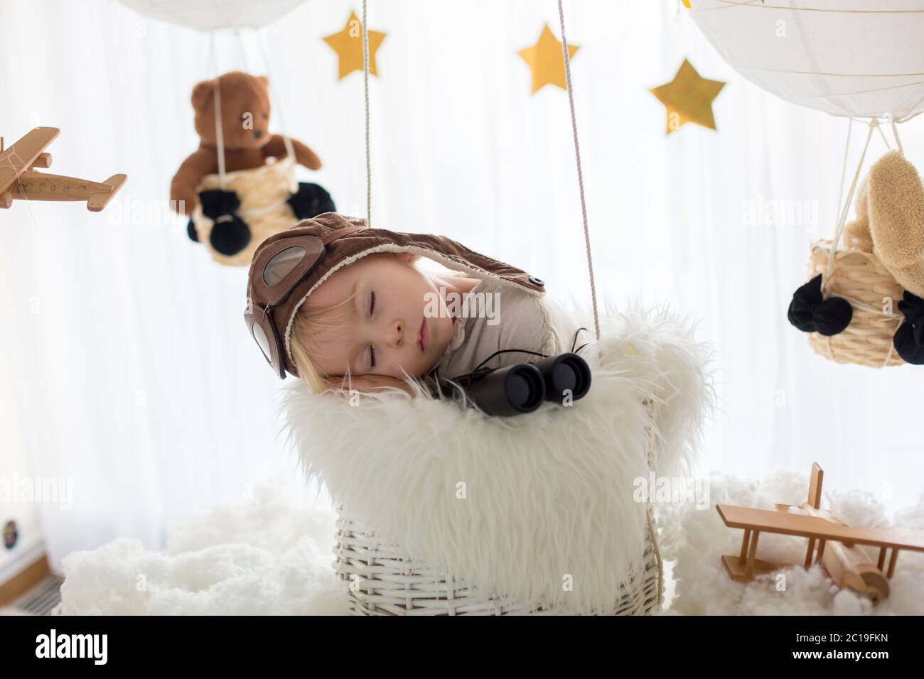 Sweet toddler boy, playing with airplane and teddy bear, decorated air ...