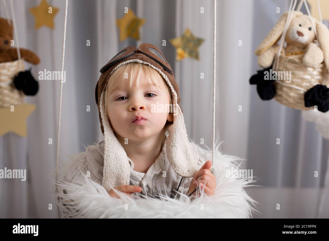 Sweet toddler boy, playing with airplane and teddy bear, decorated air ...