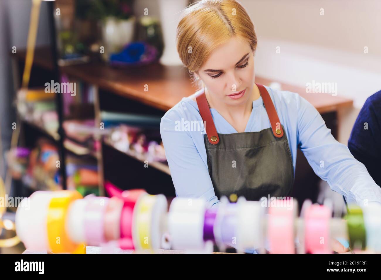 Female sales assistant working as florist and holding bouquet with ...