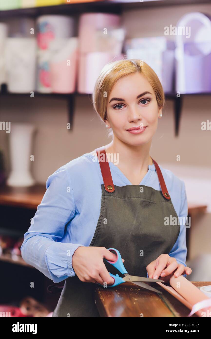 Female sales assistant working as florist and holding bouquet with ...