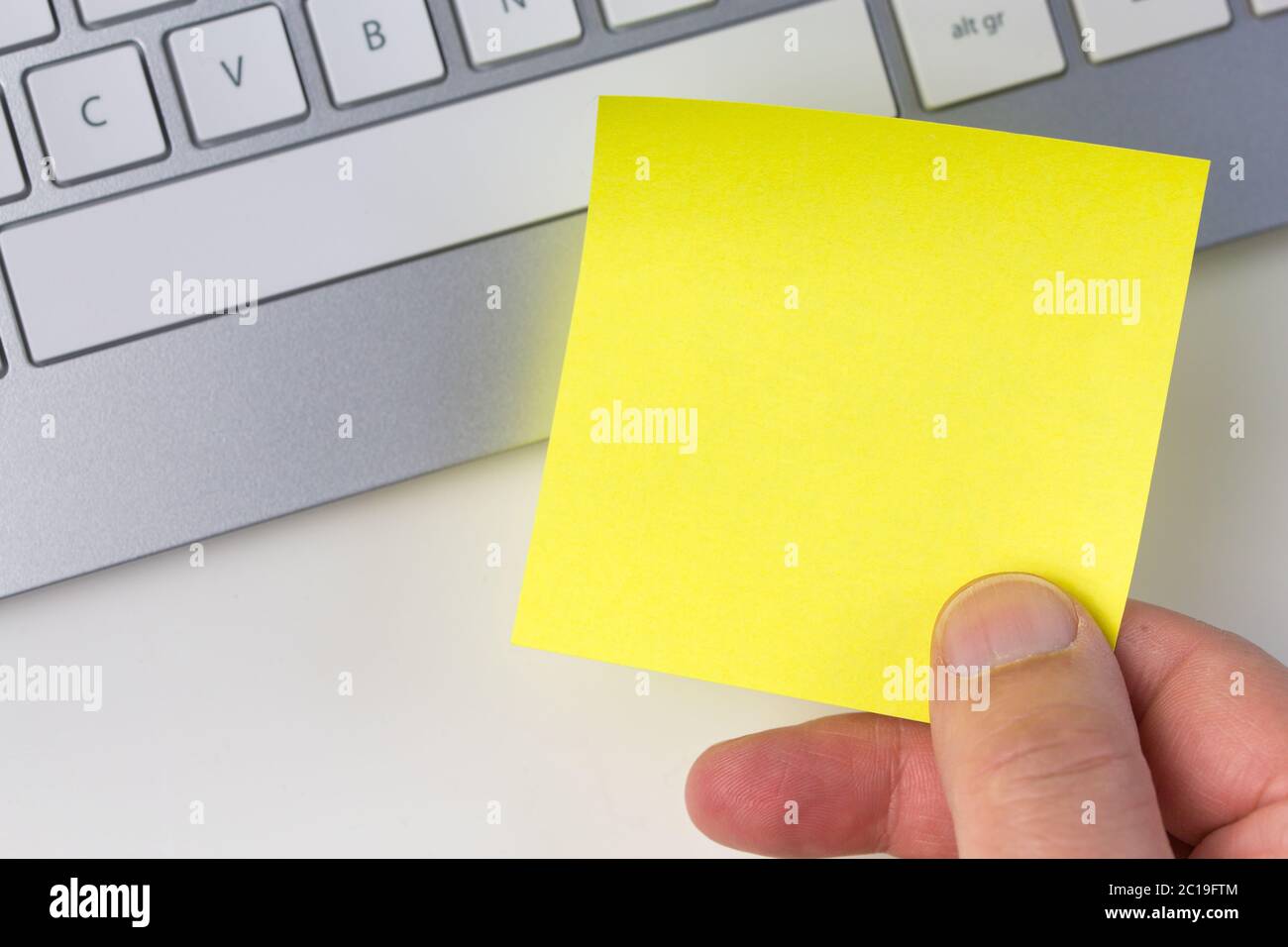 Human hand holding yellow sticky note Stock Photo - Alamy