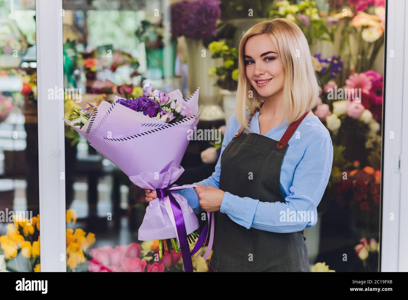 Female sales assistant working as florist and holding bouquet with ...