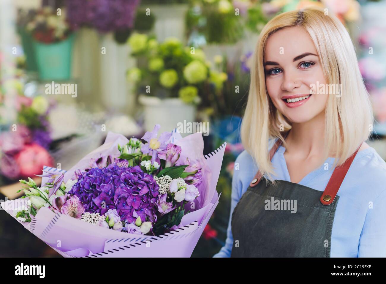 Female sales assistant working as florist and holding bouquet with ...