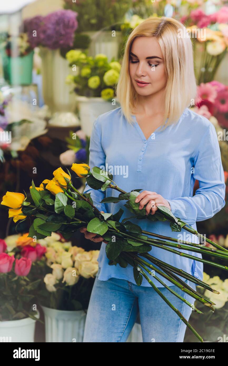 Female sales assistant working as florist and holding bouquet with ...