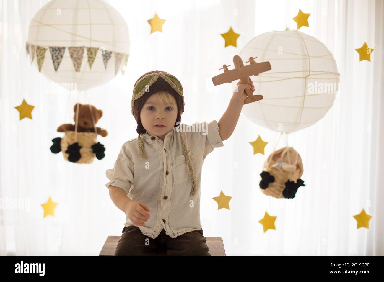 Sweet toddler boy, playing with airplane and teddy bear, decorated air ...