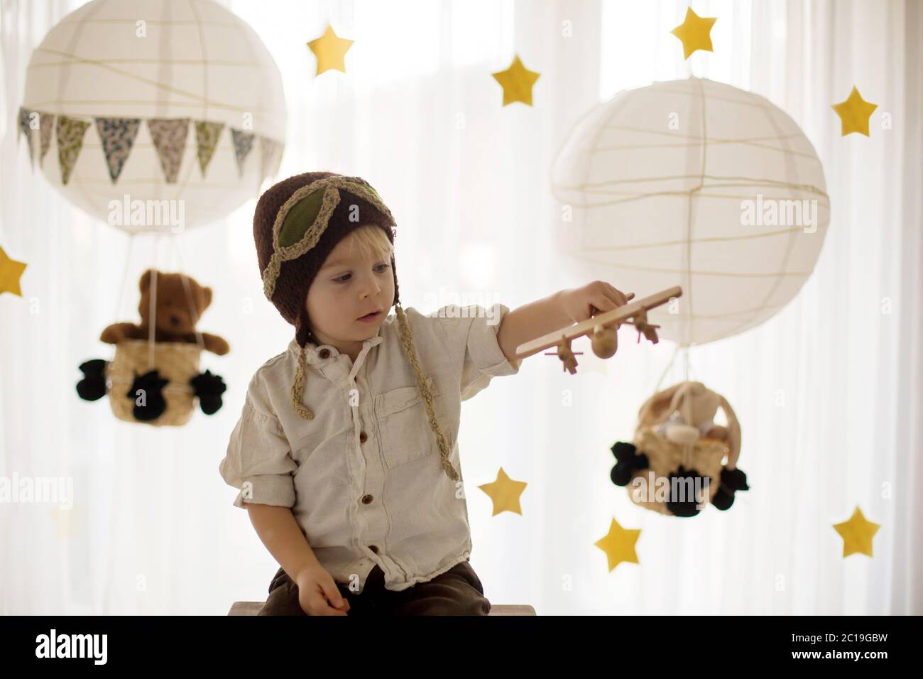 Sweet toddler boy, playing with airplane and teddy bear, decorated air ...
