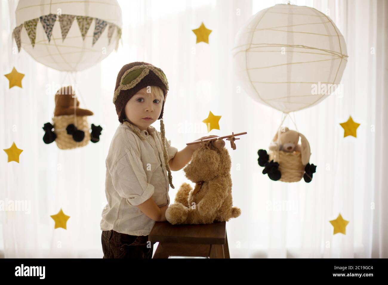Sweet toddler boy, playing with airplane and teddy bear, decorated air ...