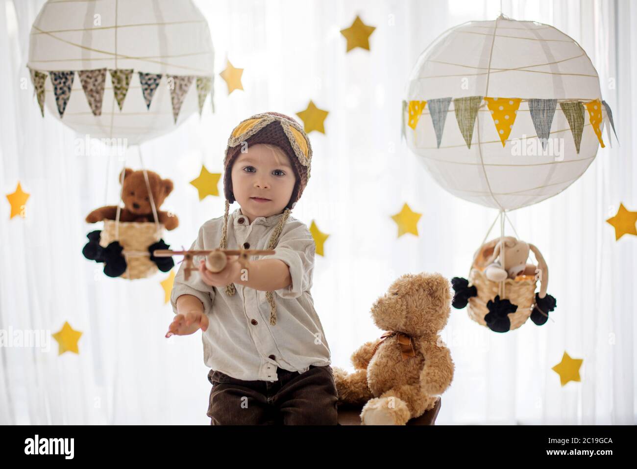 Sweet toddler boy, playing with airplane and teddy bear, decorated air ...
