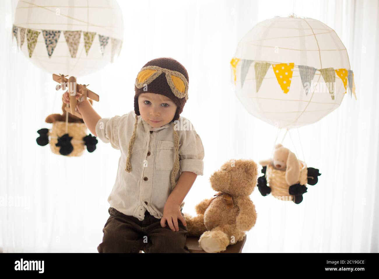 Sweet toddler boy, playing with airplane and teddy bear, decorated air ...