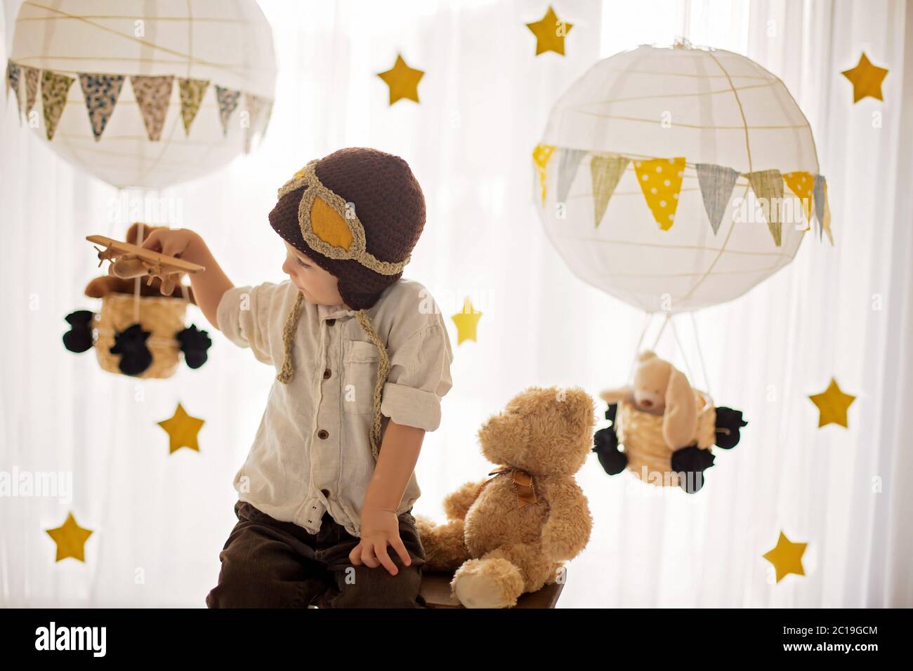 Sweet toddler boy, playing with airplane and teddy bear, decorated air ...