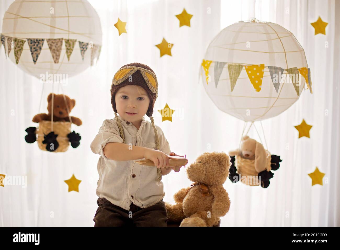 Sweet toddler boy, playing with airplane and teddy bear, decorated air ...