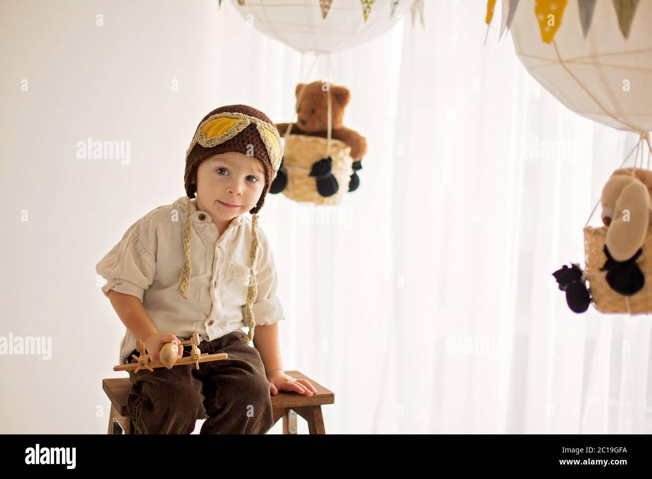 Sweet toddler boy, playing with airplane and teddy bear, decorated air ...