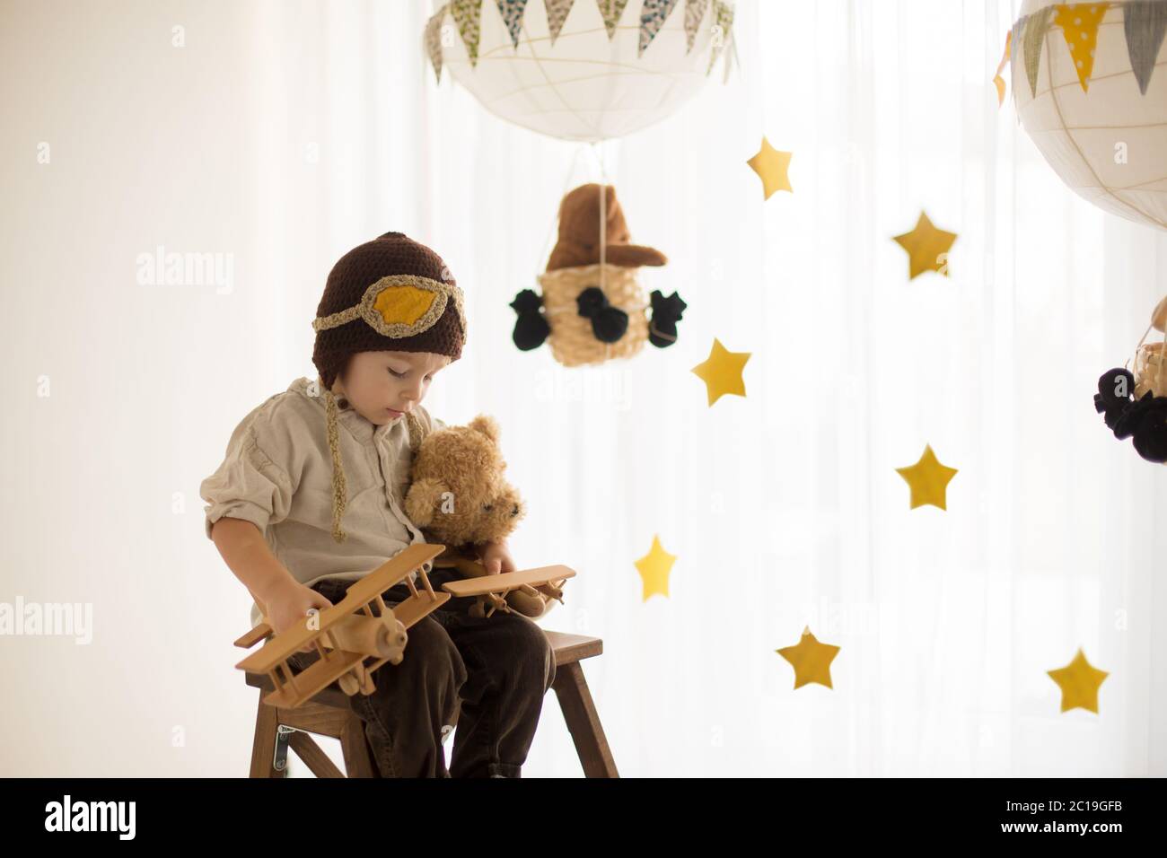 Sweet toddler boy, playing with airplane and teddy bear, decorated air ...