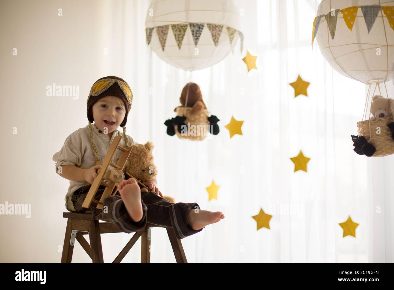 Sweet toddler boy, playing with airplane and teddy bear, decorated air ...