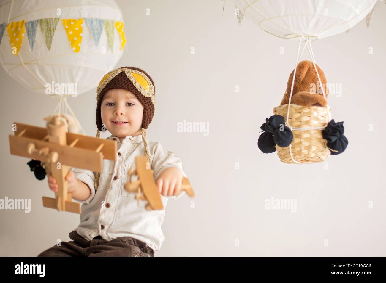 Sweet toddler boy, playing with airplane and teddy bear, decorated air ...