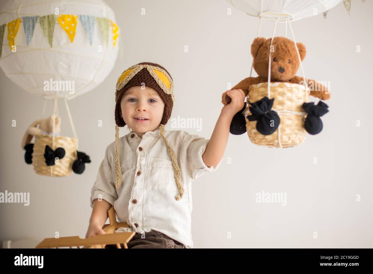 Sweet toddler boy, playing with airplane and teddy bear, decorated air ...