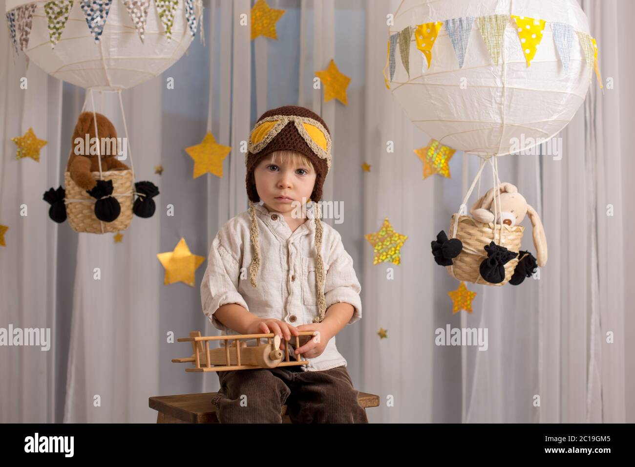 Sweet toddler boy, playing with airplane and teddy bear, decorated air ...