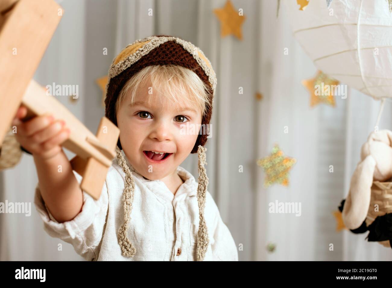 Sweet toddler boy, playing with airplane and teddy bear, decorated air ...