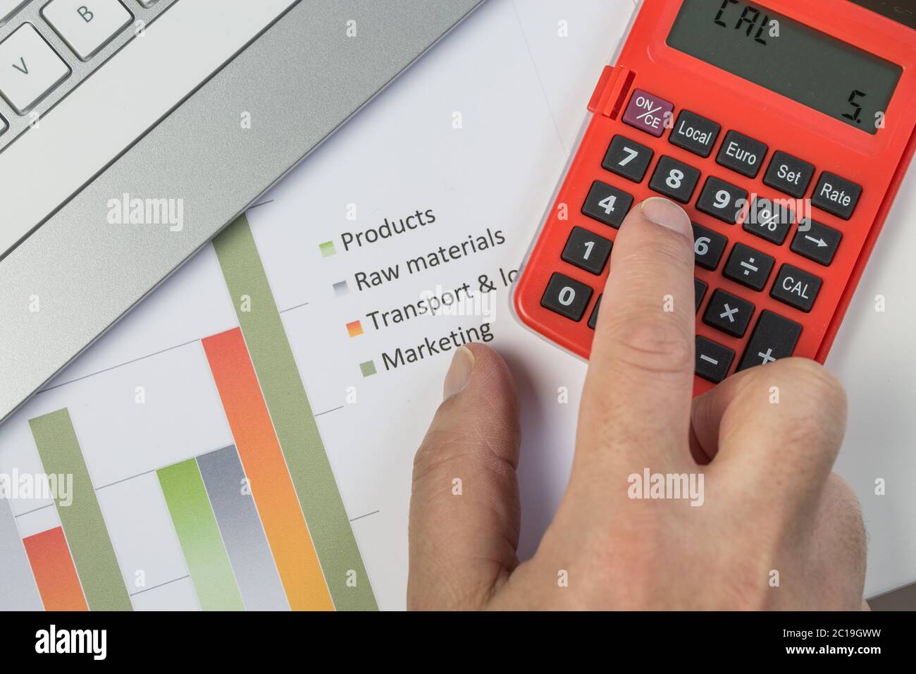 A man uses a calculator to sum up business costs according to a graph ...