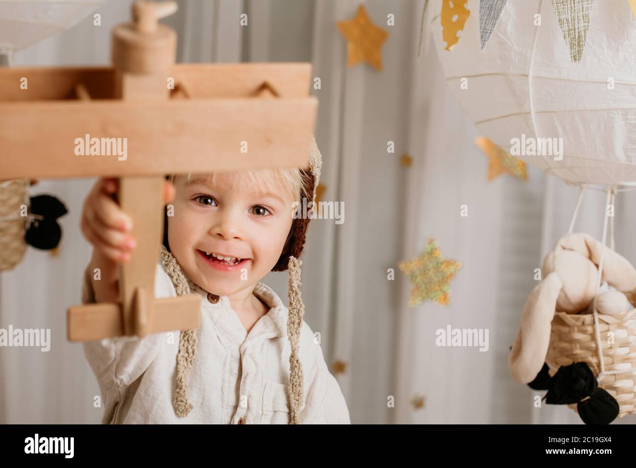 Sweet toddler boy, playing with airplane and teddy bear, decorated air ...