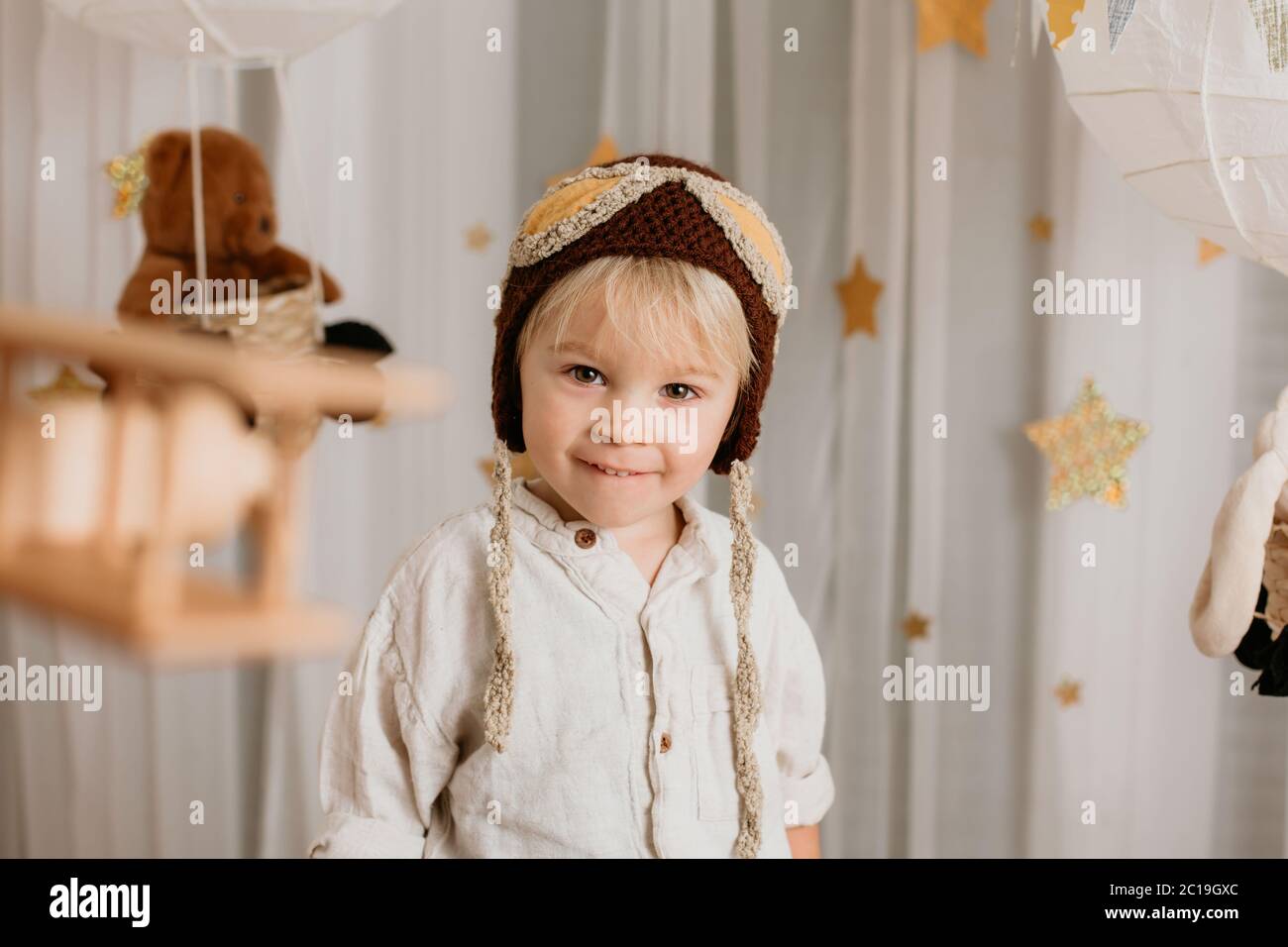 Sweet toddler boy, playing with airplane and teddy bear, decorated air ...