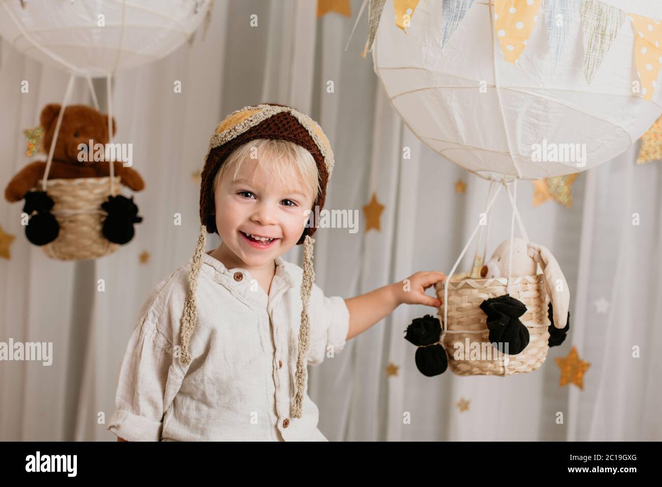 Sweet toddler boy, playing with airplane and teddy bear, decorated air ...