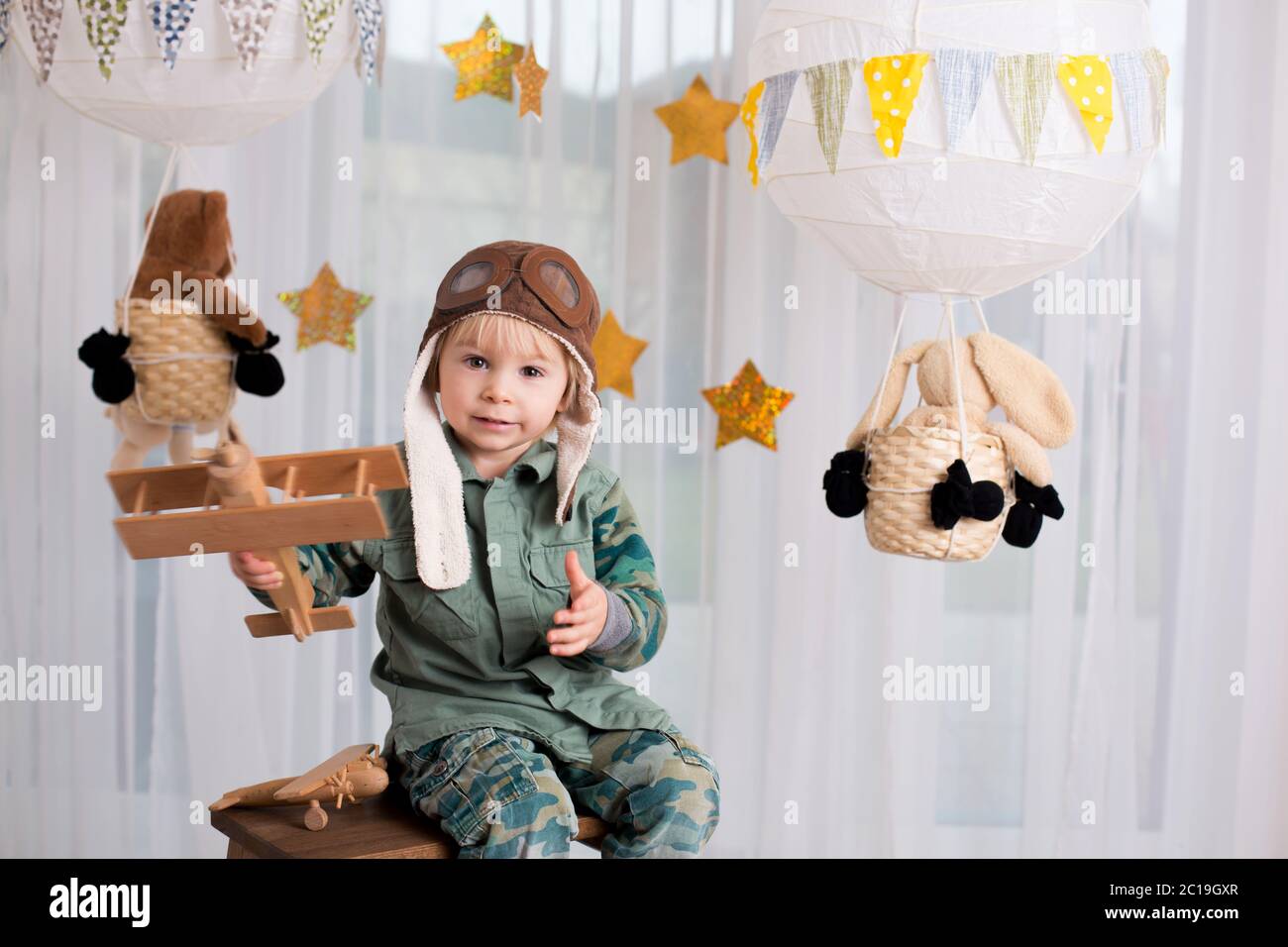 Sweet toddler boy, playing with airplane and teddy bear, decorated air ...