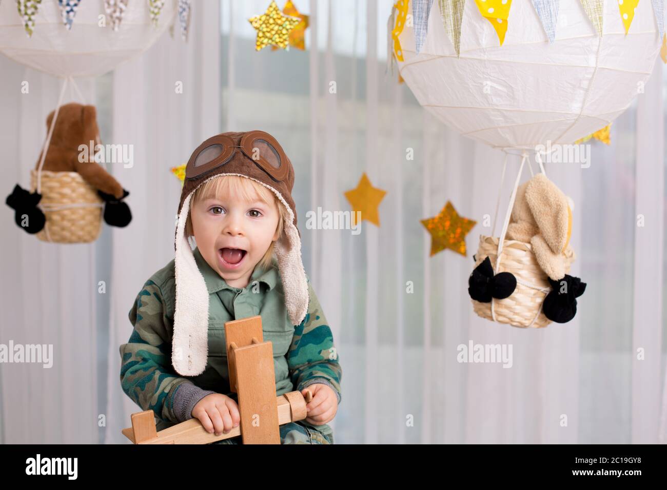 Sweet toddler boy, playing with airplane and teddy bear, decorated air ...