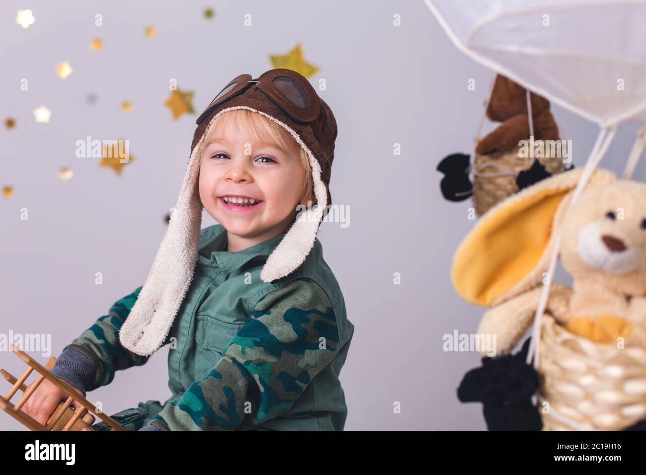 Sweet toddler boy, playing with airplane and teddy bear, decorated air ...
