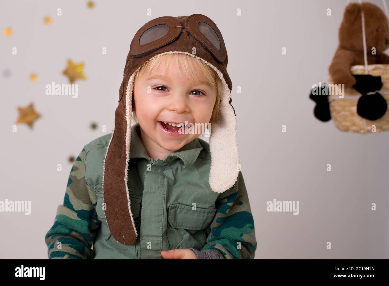 Sweet toddler boy, playing with airplane and teddy bear, decorated air ...