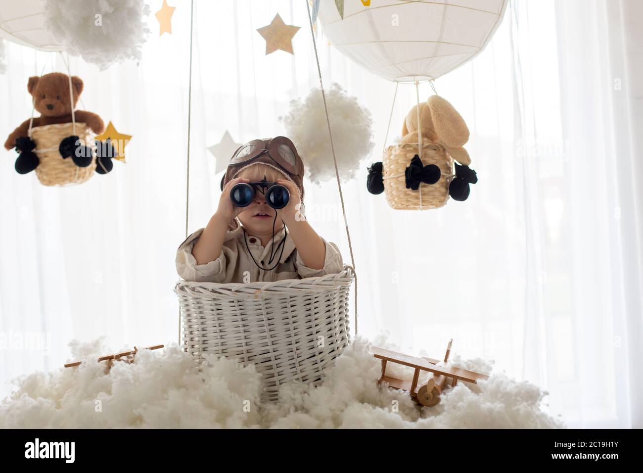 Sweet toddler boy, playing with airplane and teddy bear, decorated air ...