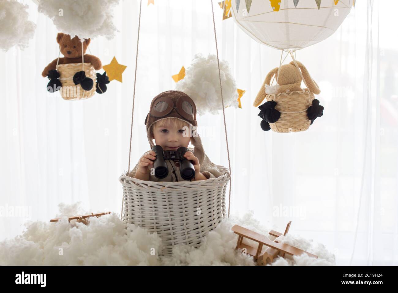 Sweet toddler boy, playing with airplane and teddy bear, decorated air ...