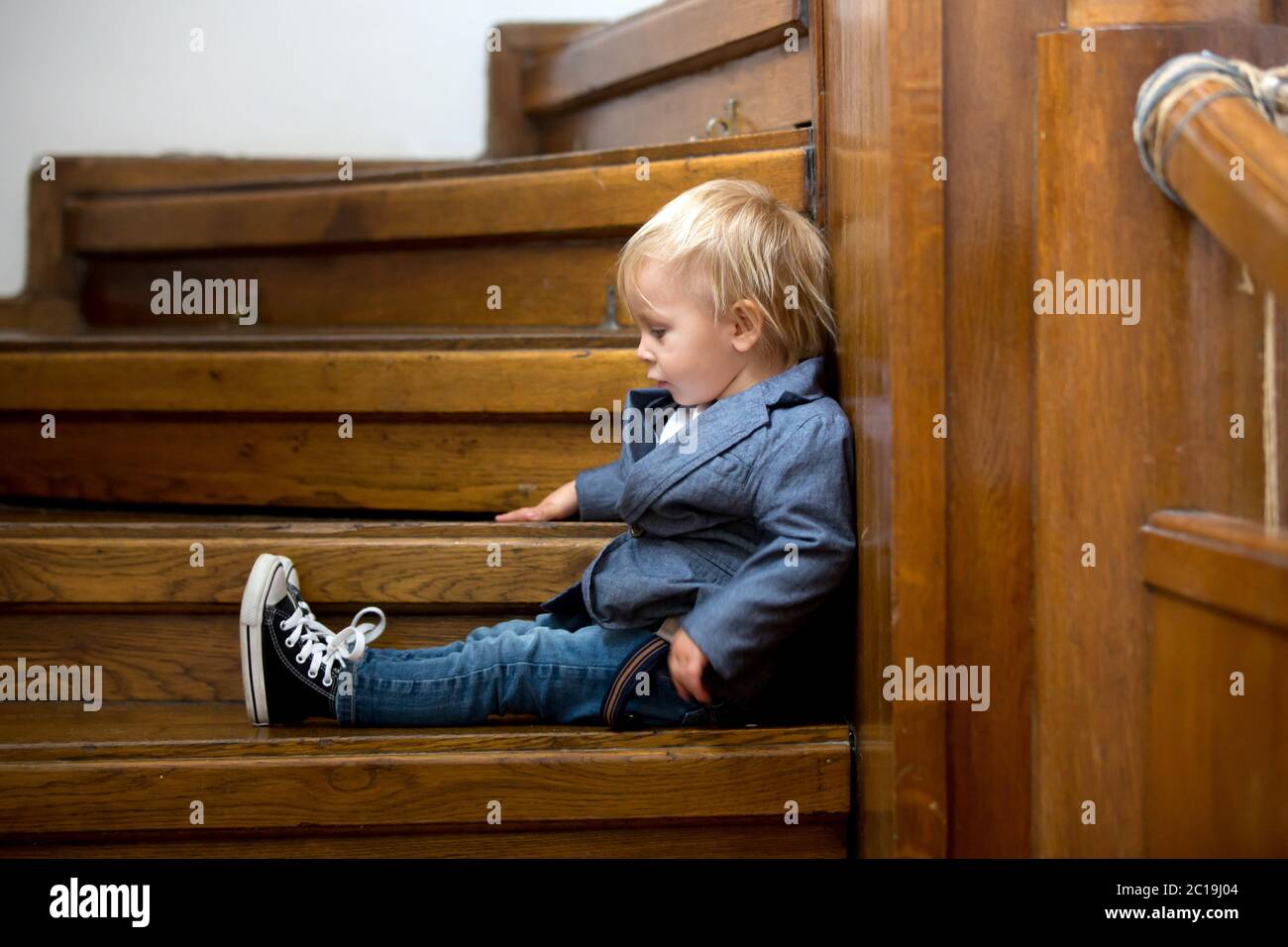 Sad child, sitting on a staircase in a big house, concept for bullying ...