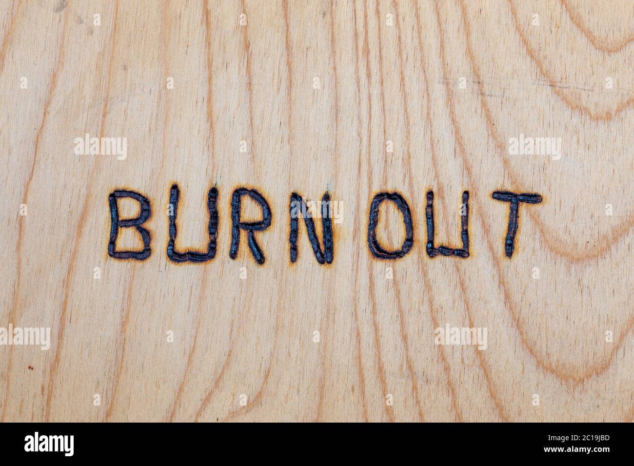 the words burn out handwritten with woodburner on flat plywood surface ...