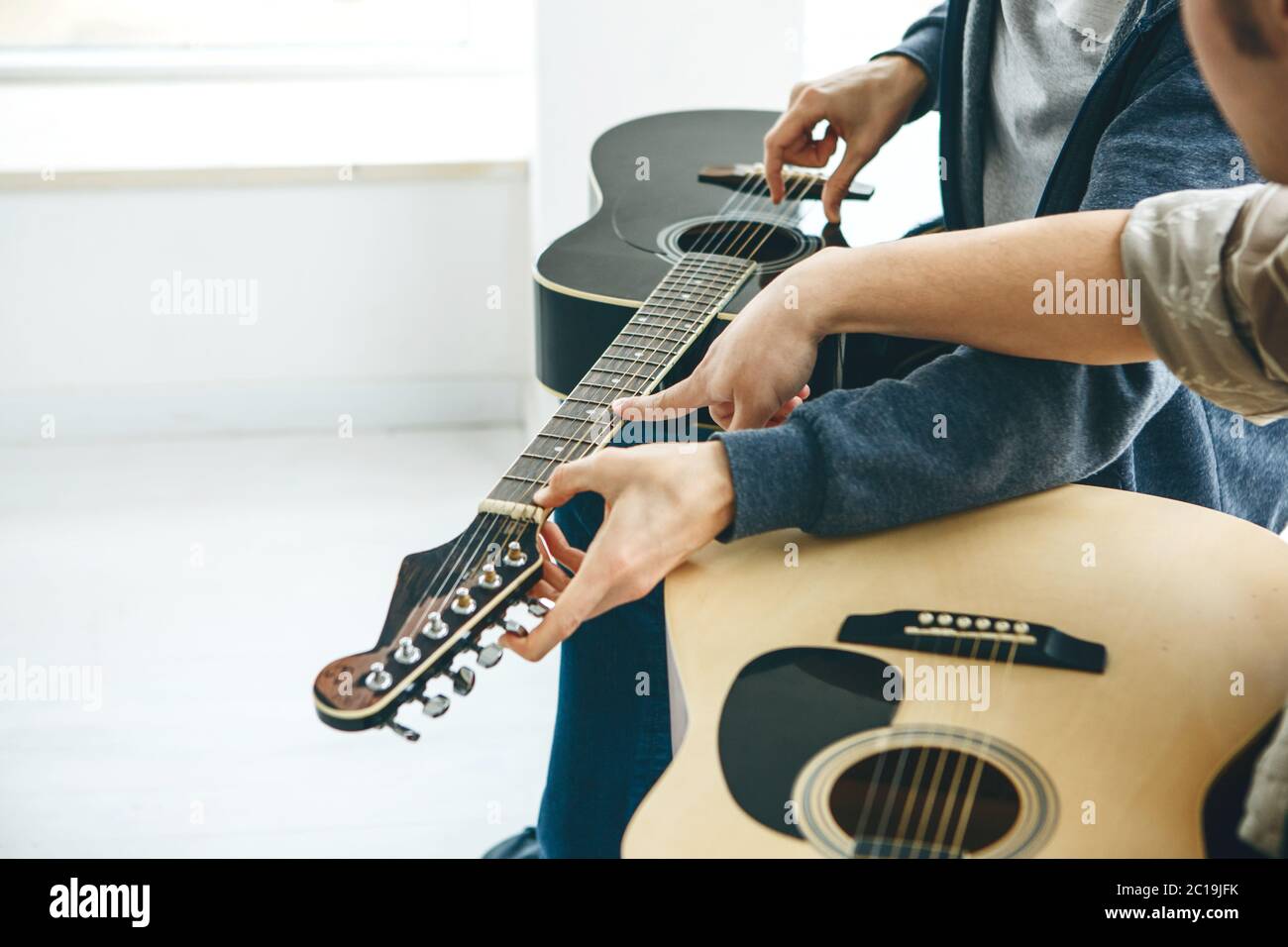 Learning to play the guitar. The teacher helps the student tune the ...