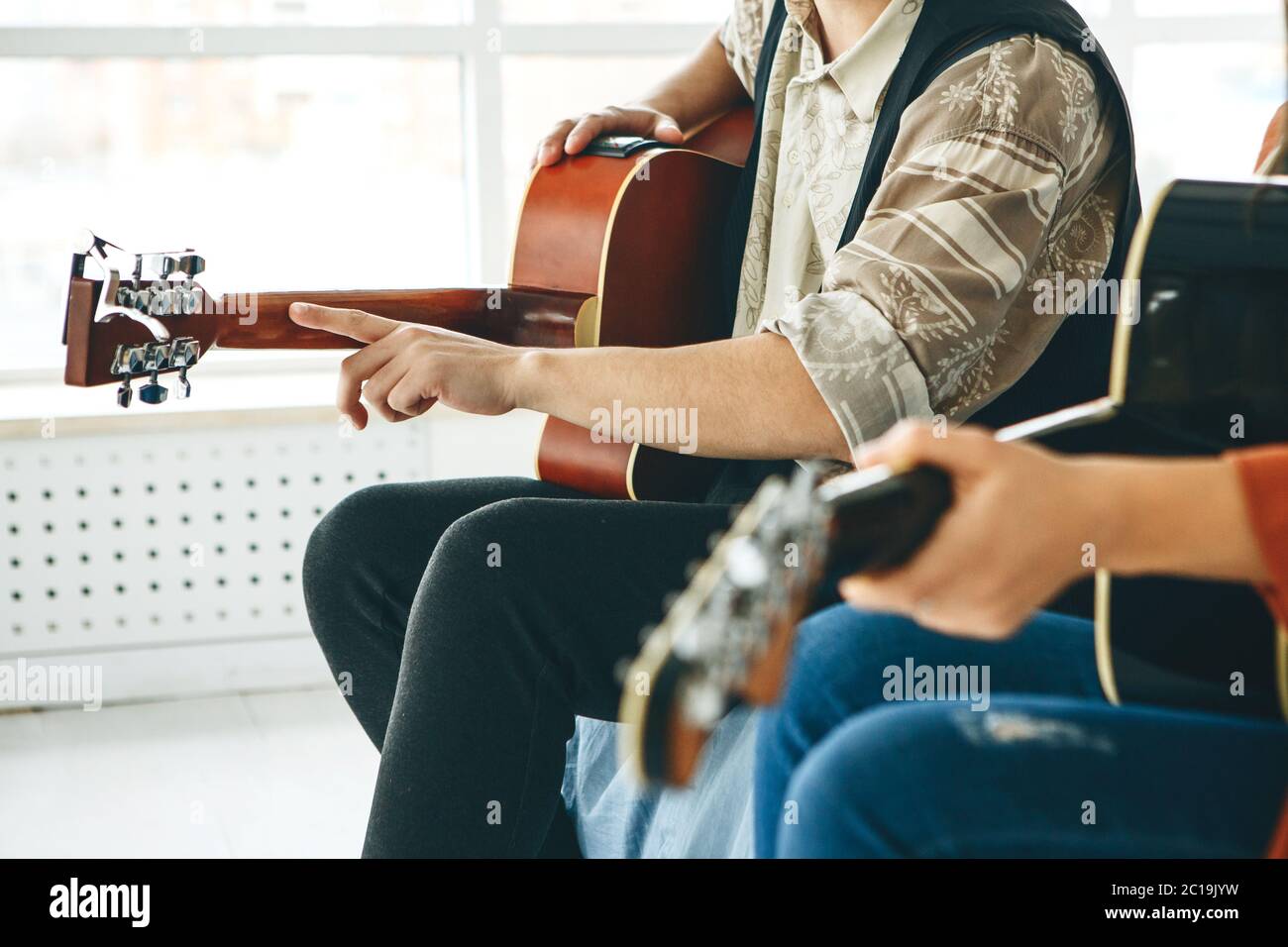 Learning to play the guitar. The teacher explains to the student the ...