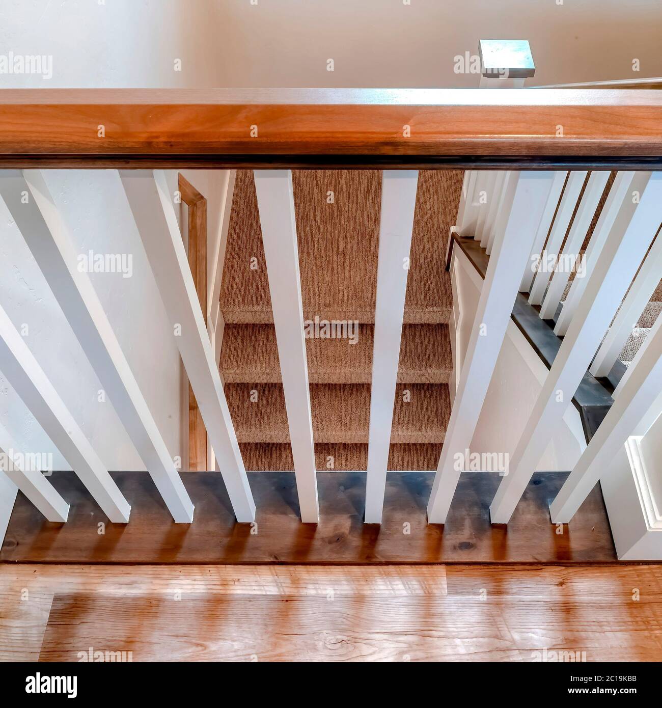 Square U shaped staircase with white baluster brown handrail and carpet ...