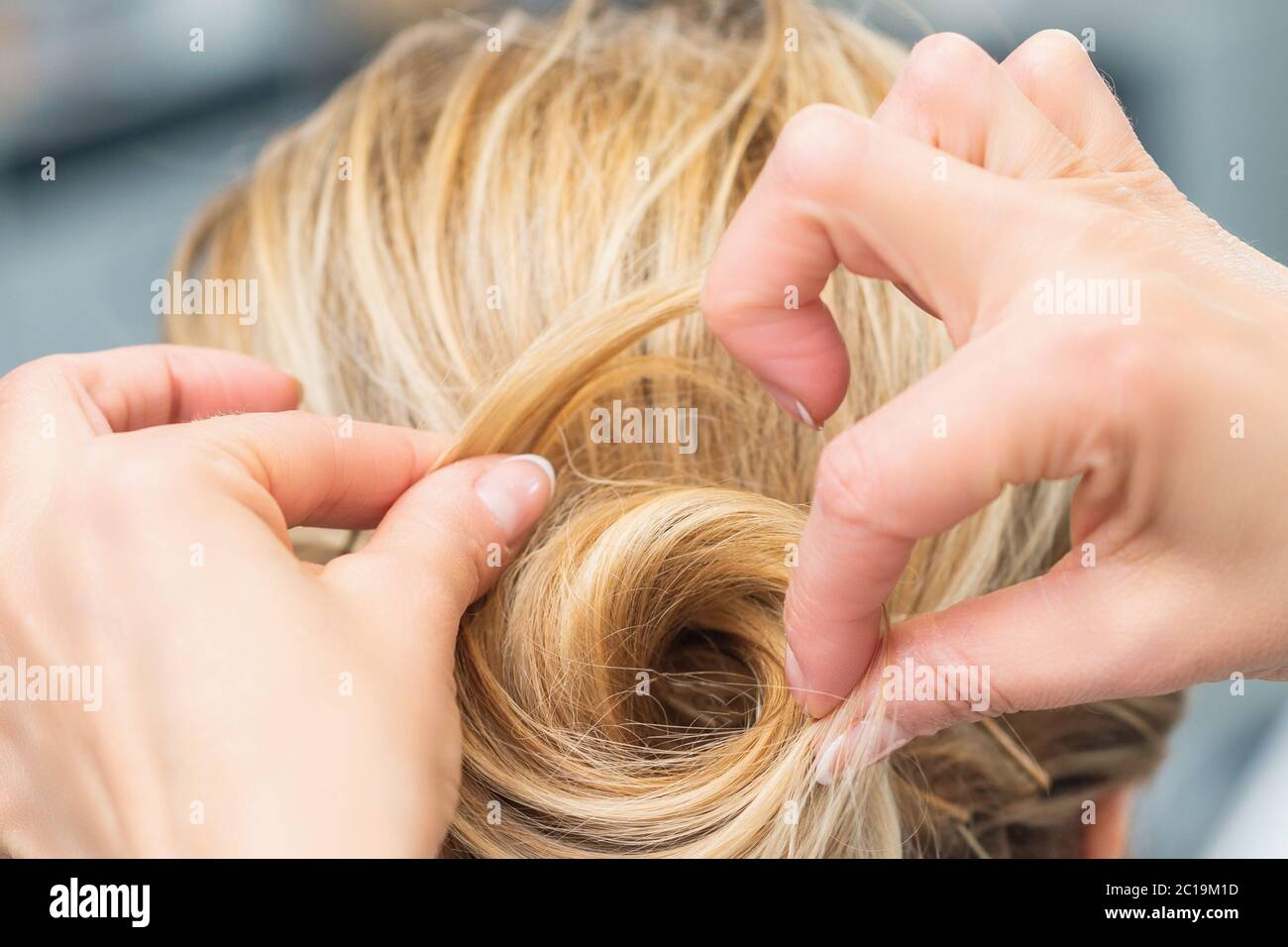 Close up rear view of hairdresser making hairstyle for long hair of ...