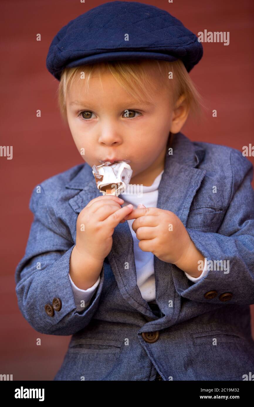 Cute child, boy in vintage cloths, eating lollipop ice cream, sitting ...