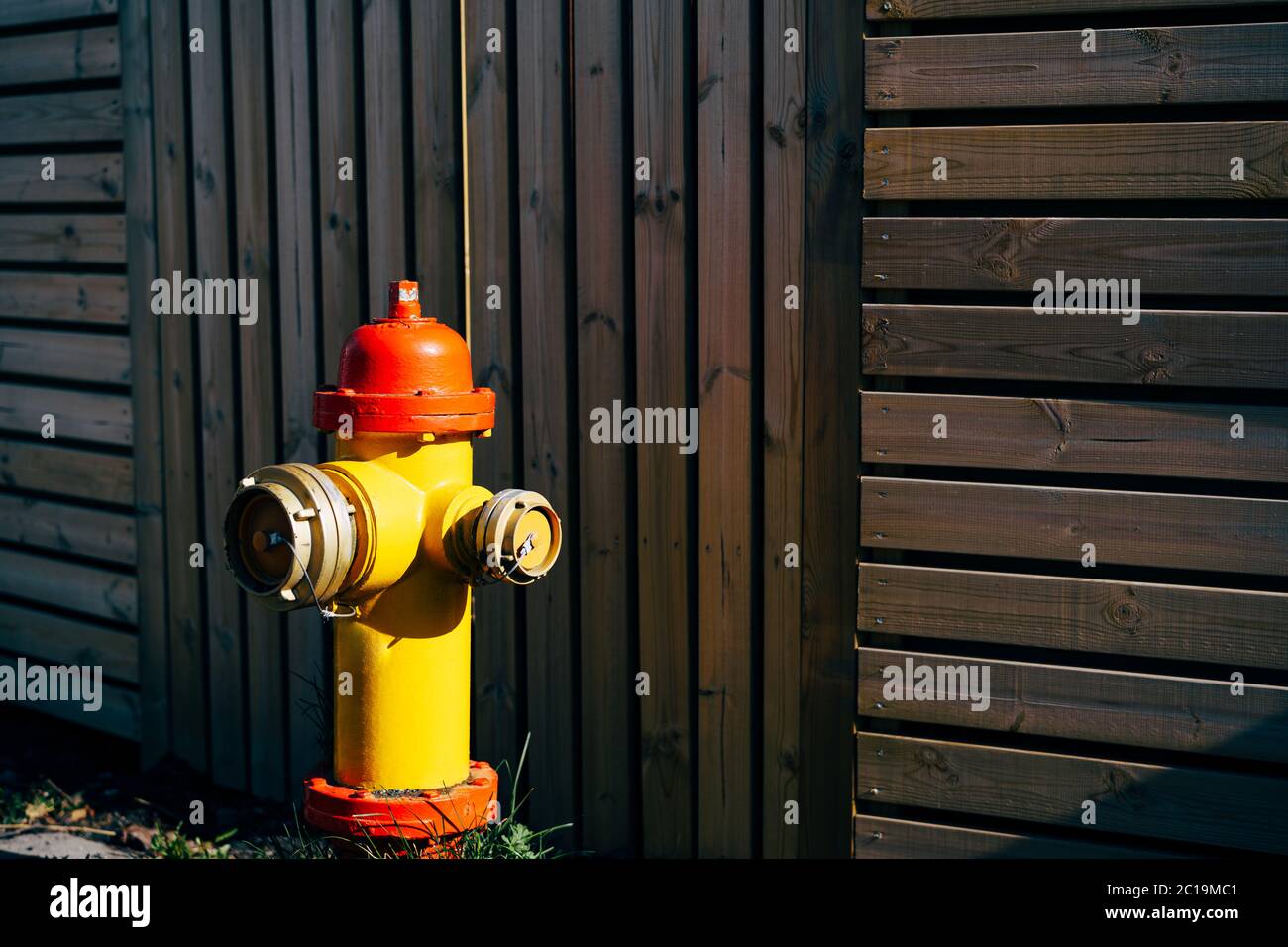 Yellow fire hydrant with red cap and silver lids, On a wooden ...