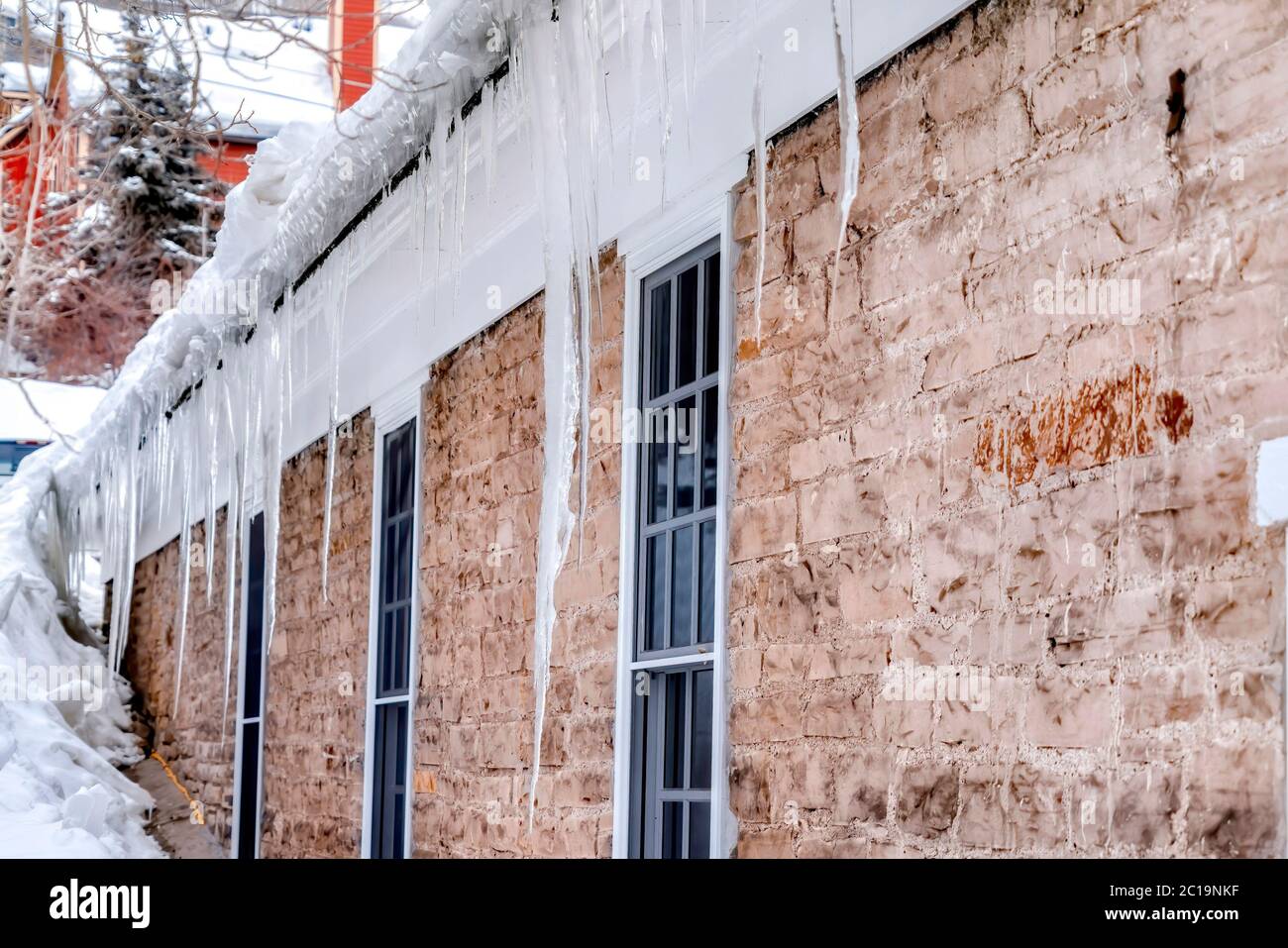 Square Sharp spiked icicles against windows and stone exterior wall of ...