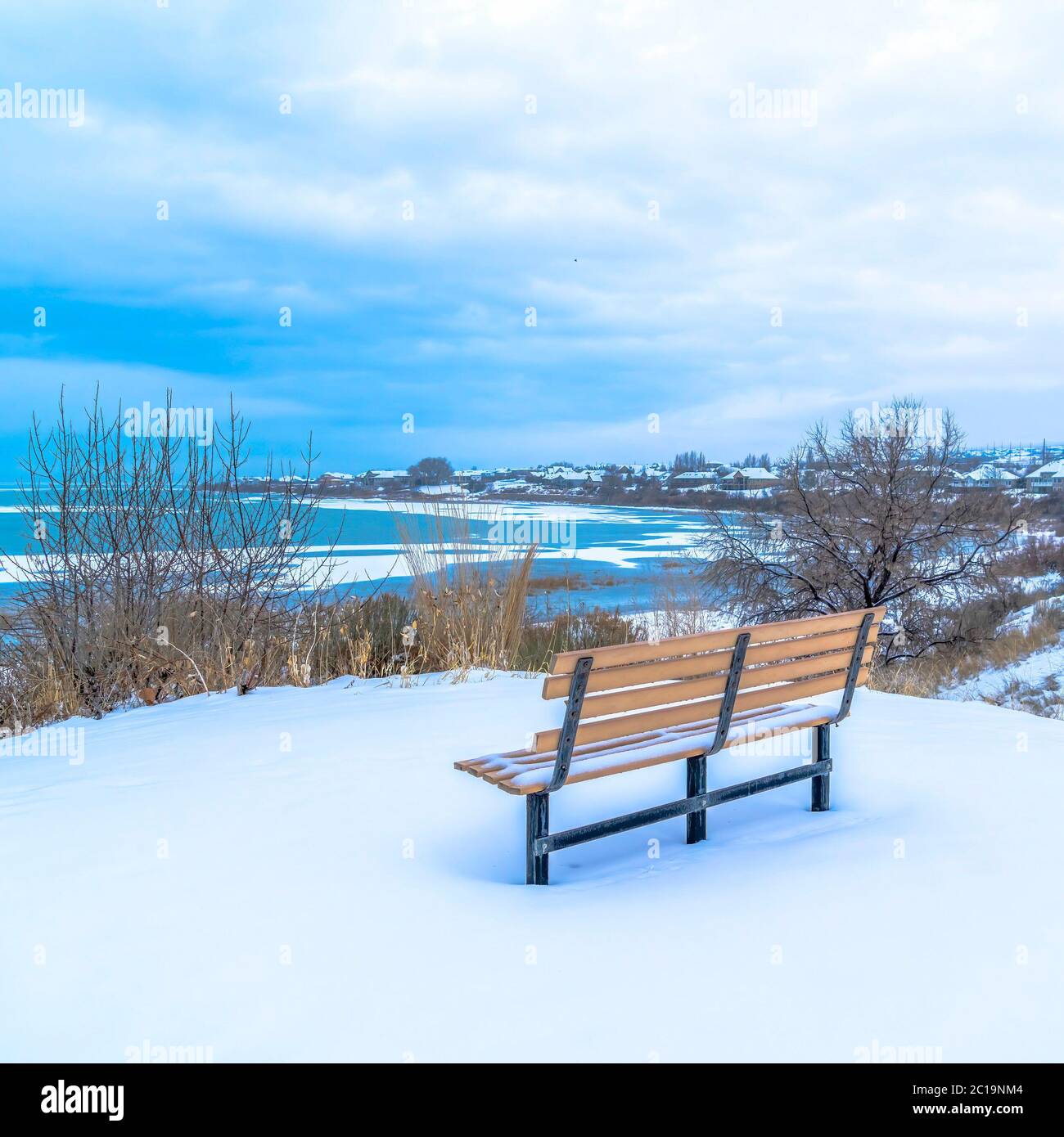 Square Bench on a snowy terrain with frozen Utah Lake and overcast sky ...