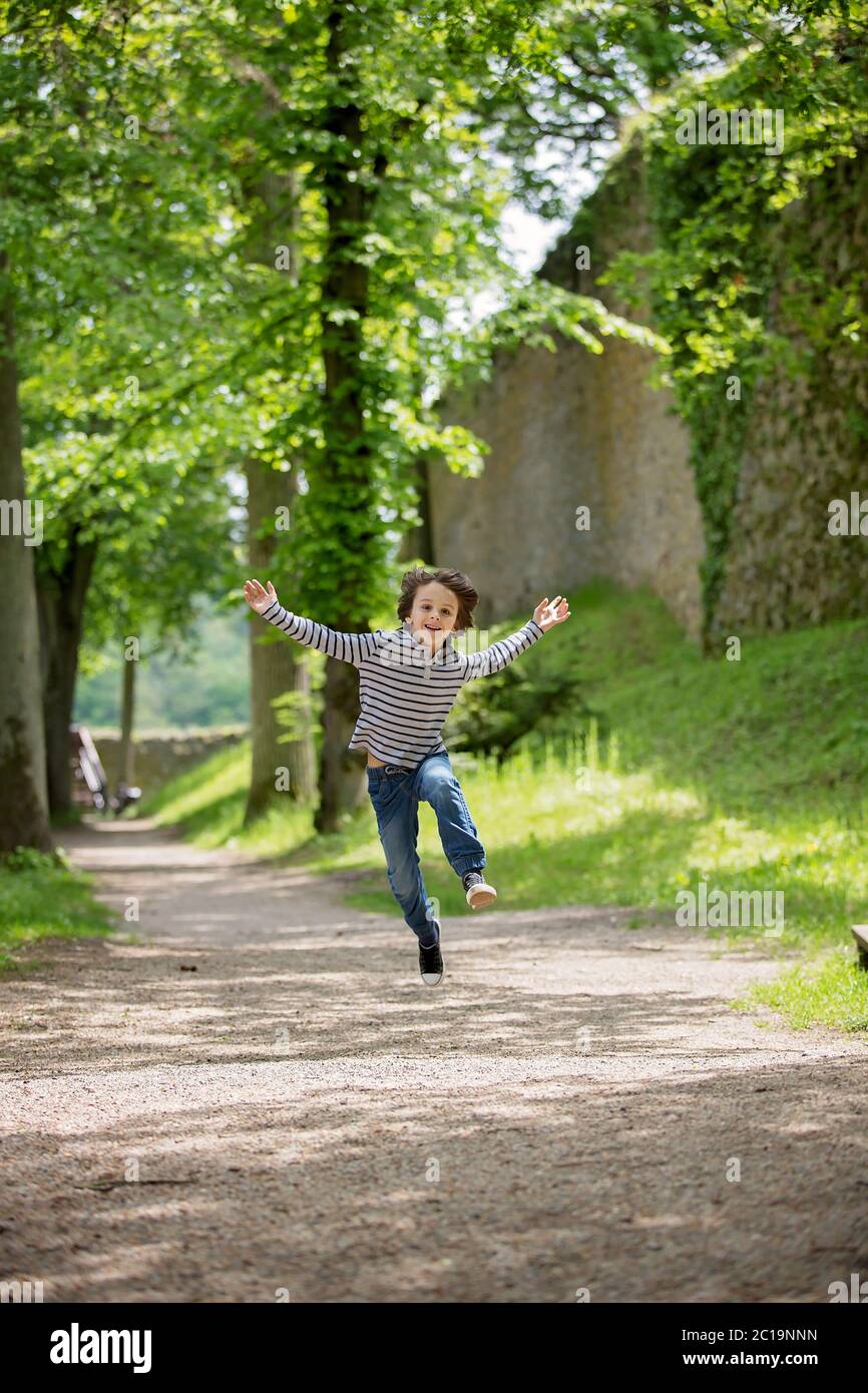 Happy Child, boy, running and jumpring on path in park with trees and ...