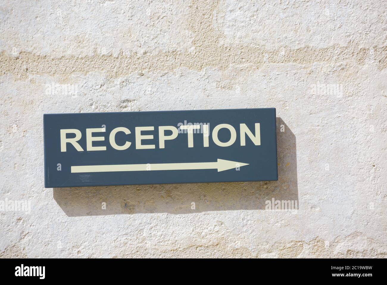 sign attached to a white wall indicating where the reception area is ...
