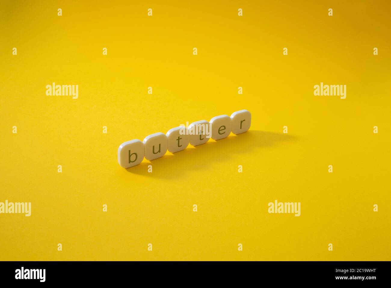 Alphabet butter word block with yellow background Stock Photo - Alamy
