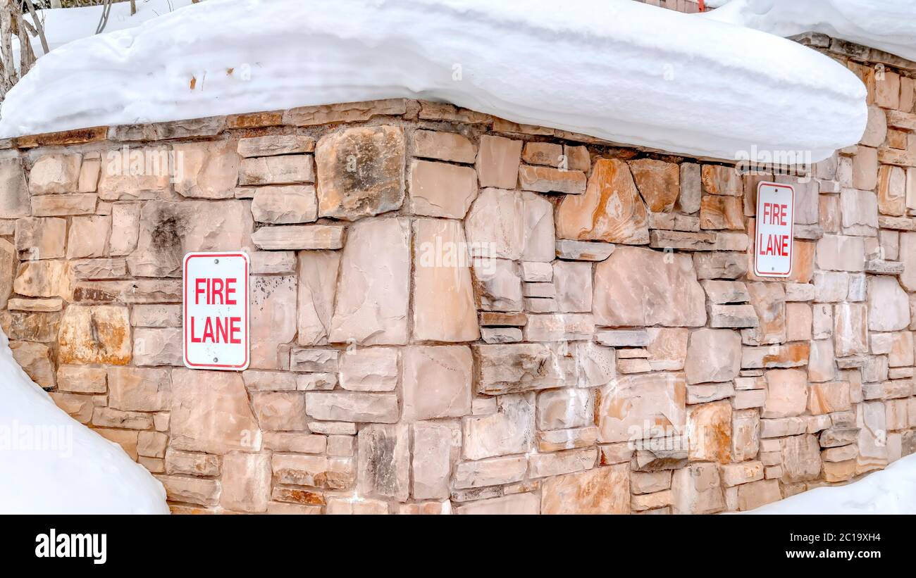 Panorama Stone retaining wall with Fire Lane sign on a hill with thick ...