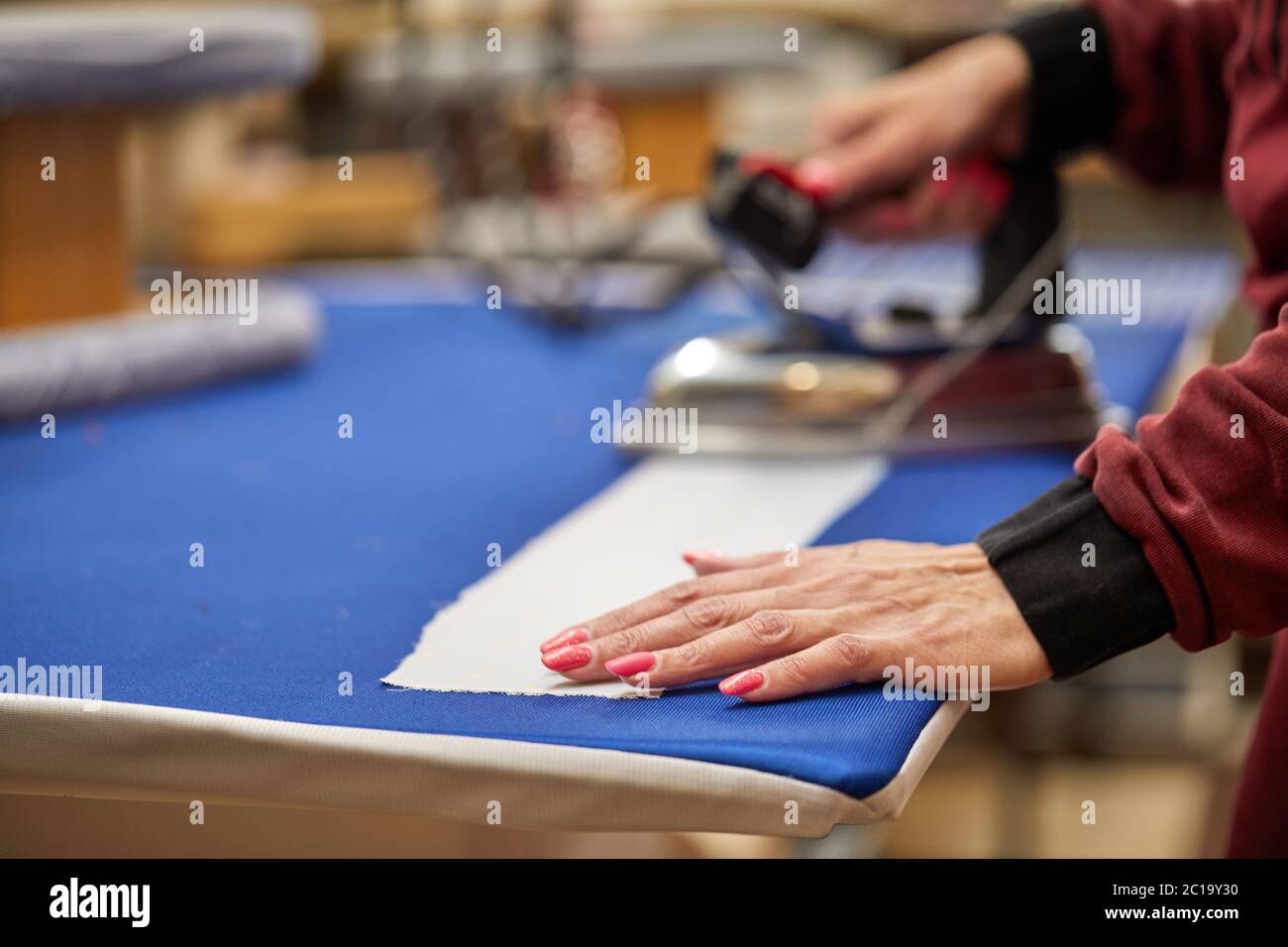 Tailor ironing the fabric. seamstress irons dress in a sewing workshop ...