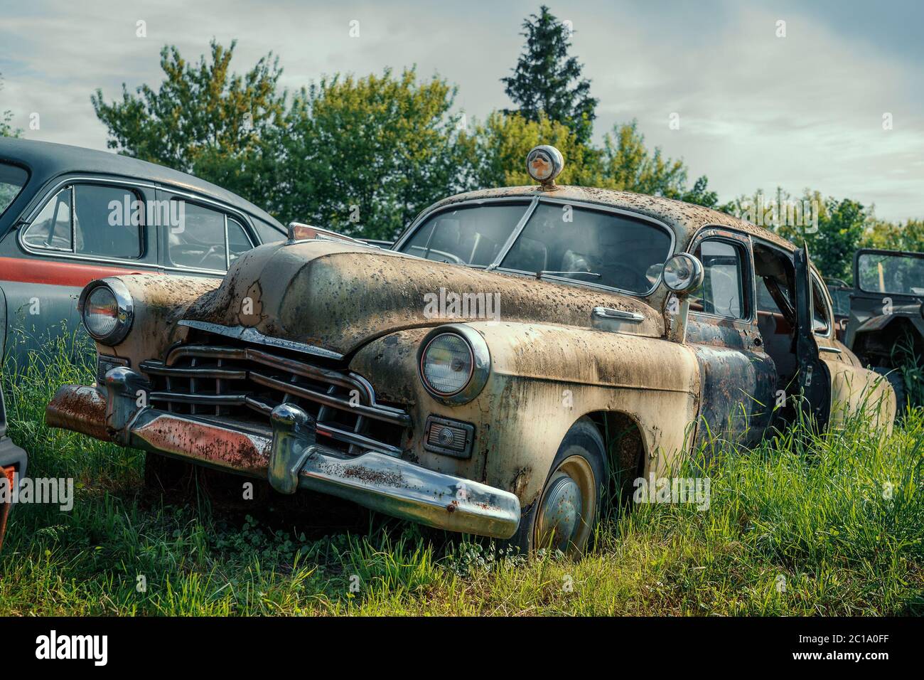 Vintage rusty retro car among other cars in green grass Stock Photo - Alamy